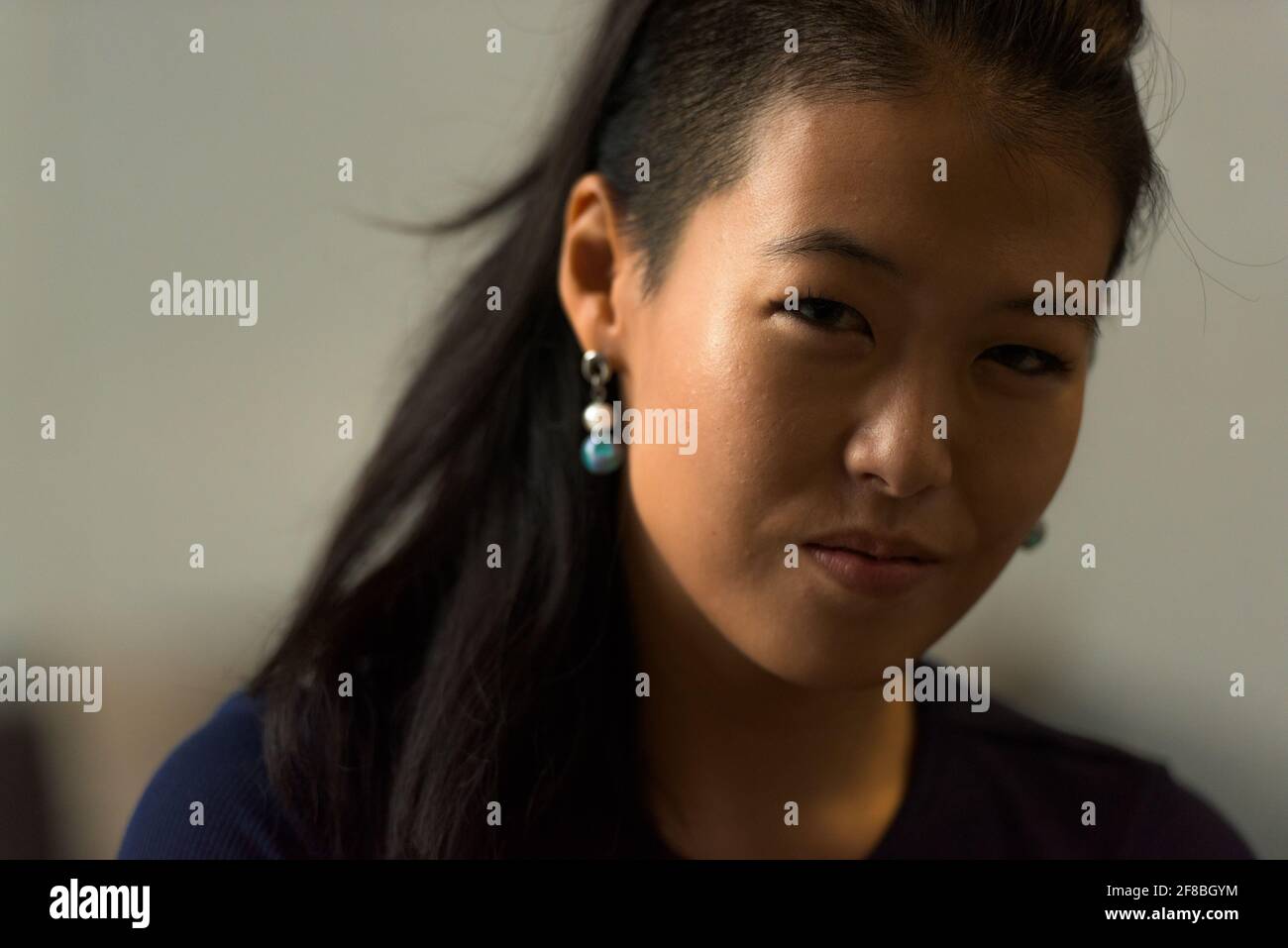 Close-up portrait of beautiful rebel Asian woman face smiling outdoors ...