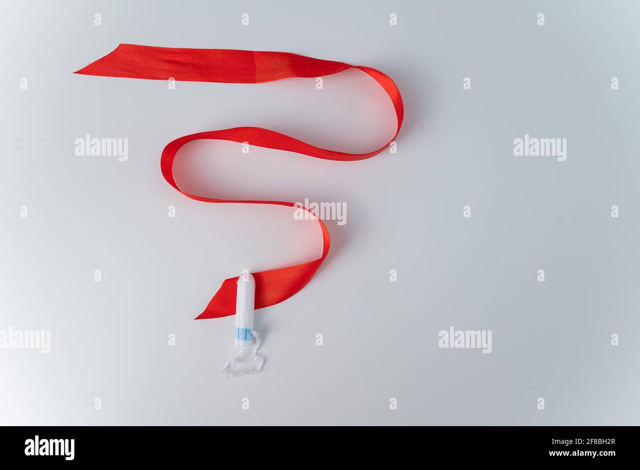 Tampon and red satin ribbon on a white background. Means of intimate ...