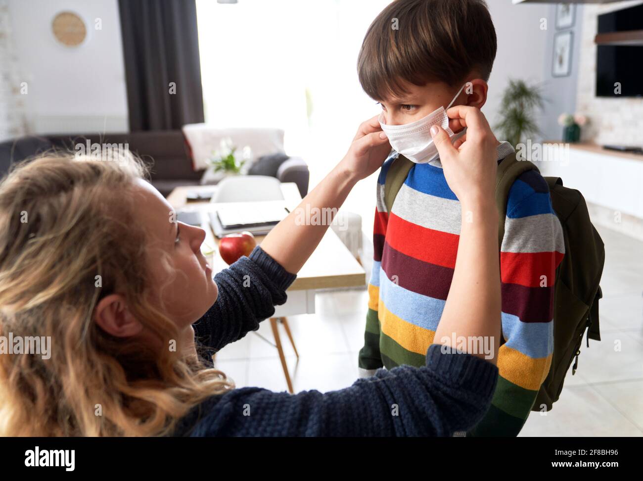 Mother puts on a protective mask for her son Stock Photo - Alamy