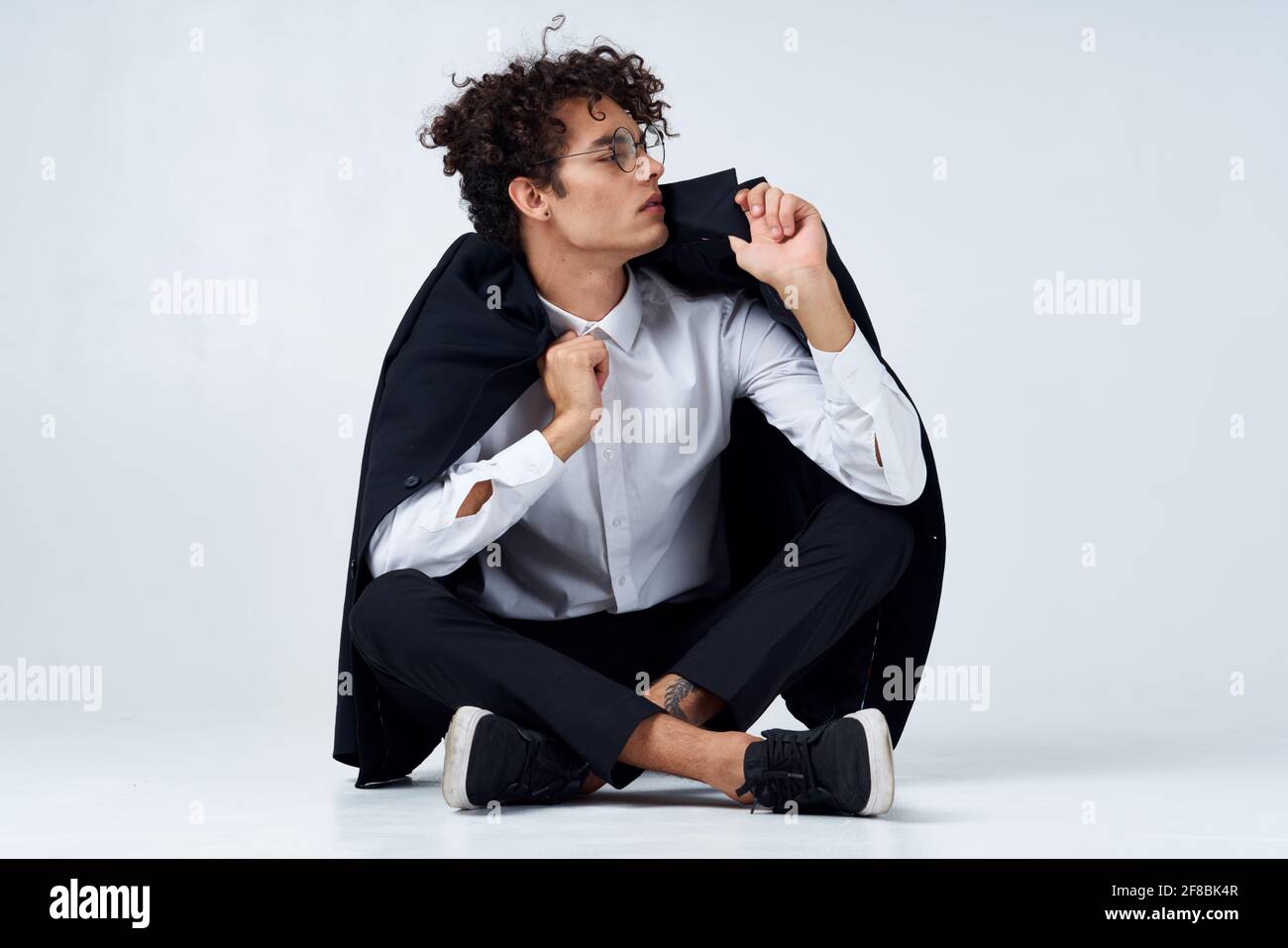 curly-haired guy straightens his jacket over his shoulders and sits on ...