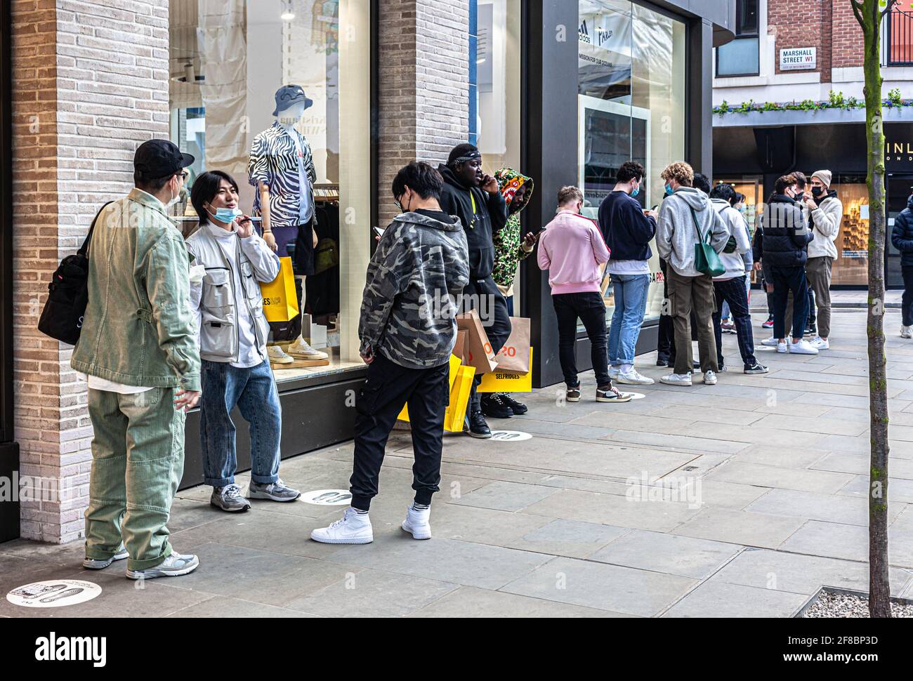 Shoppers standing in queue outside a sports shop, Soho, London, England ...