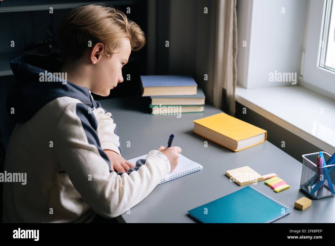 High-angle view of back view of pupil boy reading paper study book ...