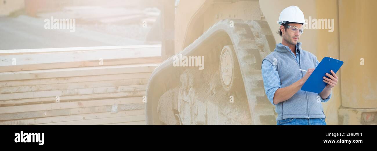 Smilling caucasian male construction worker writing on a clipboard ...