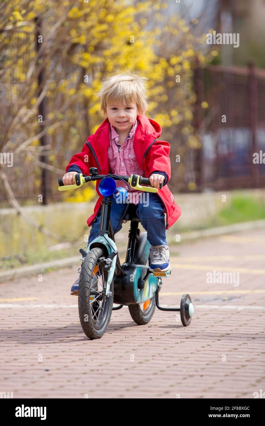 Little child, blond boy, learning how to ride a bicycle in the park ...