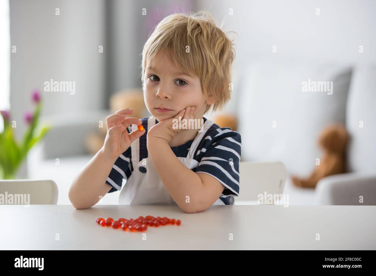 Cute little child, toddler boy, eating alfa omega 3 child suplement ...