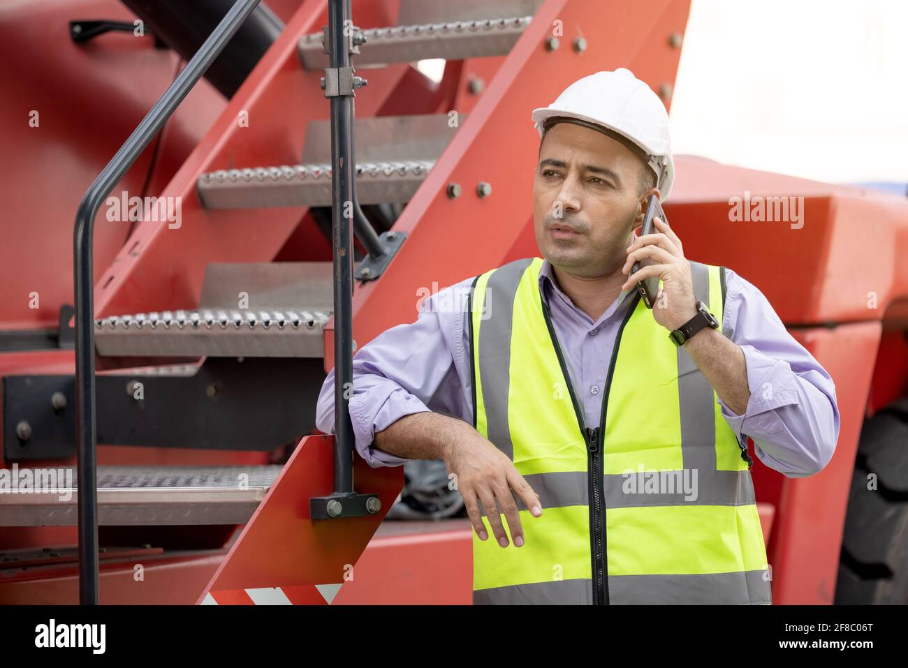 Worker helmet standing and talking on mobile phone at logistic cargo ...