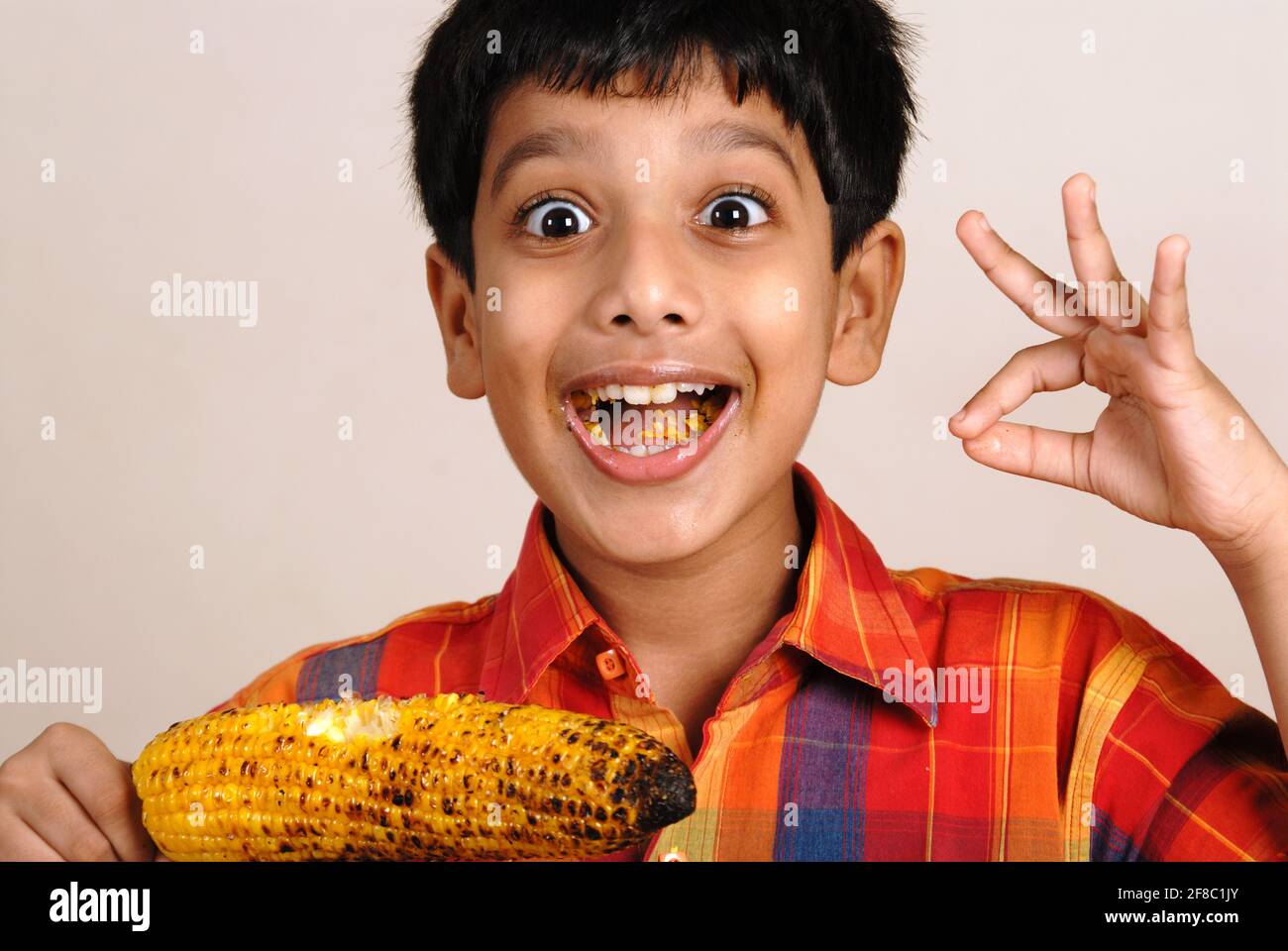 Eight years old happy indian cute little boy eating Yellow hybrid sweet ...