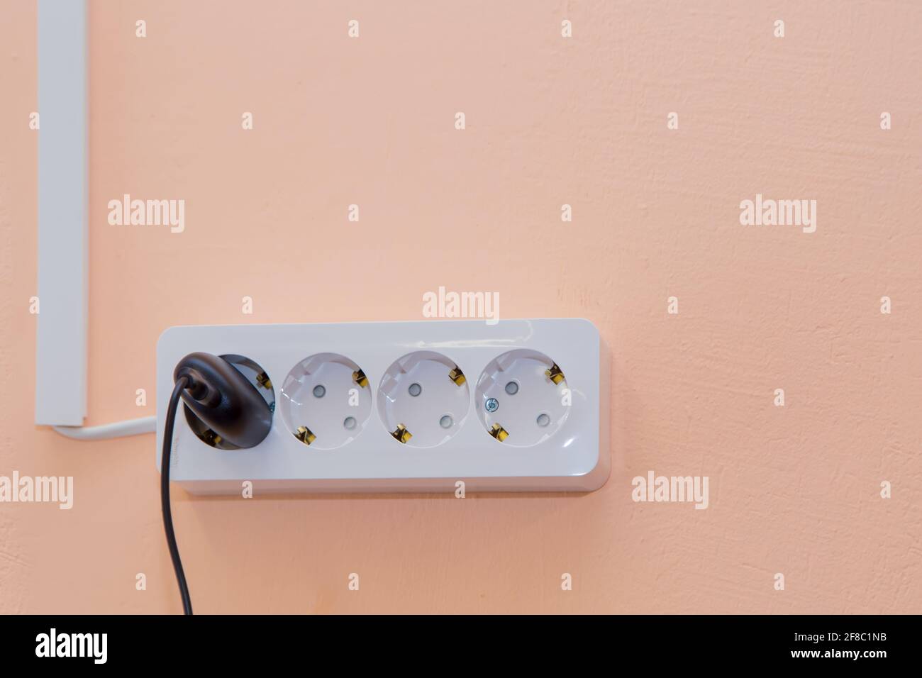 An outlet with a plugged-in plug and wires going side by side in a box ...