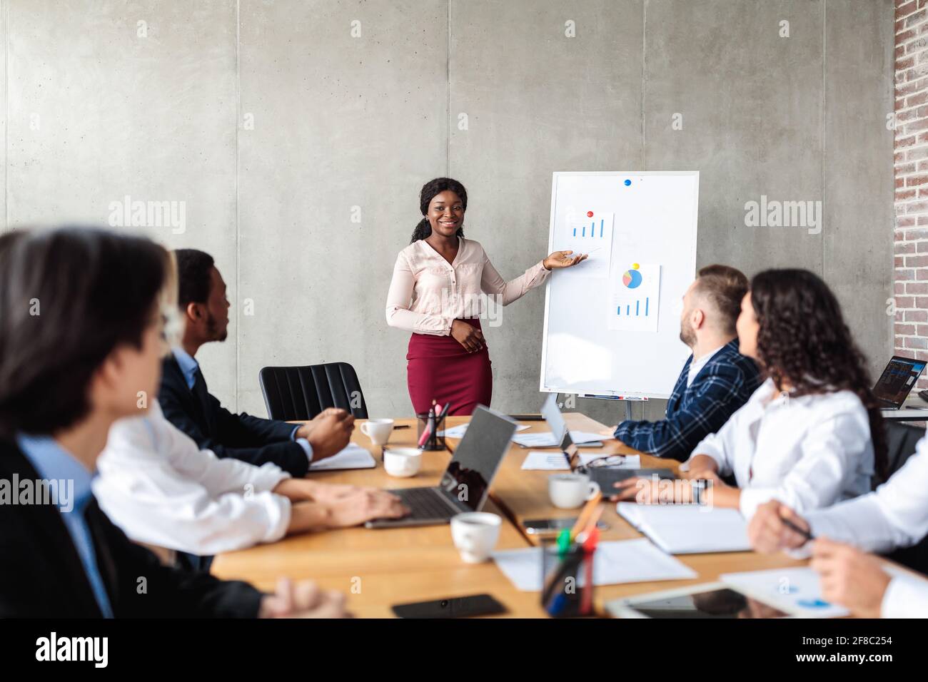 Businesswoman Pointing At Charts On Blackboard During Corporate Meeting ...
