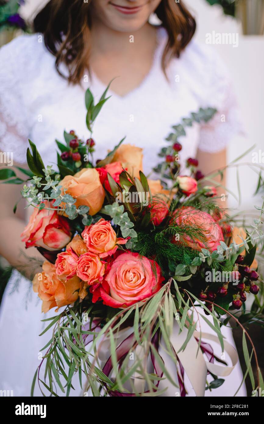 Bride holds beautiful vibrant wedding bouquet of orange and red roses ...