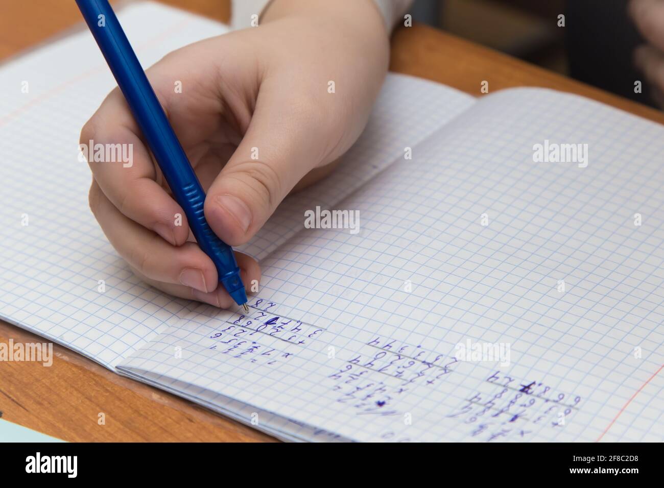The girls hands with a blue fountain pen solve examples in close-up ...