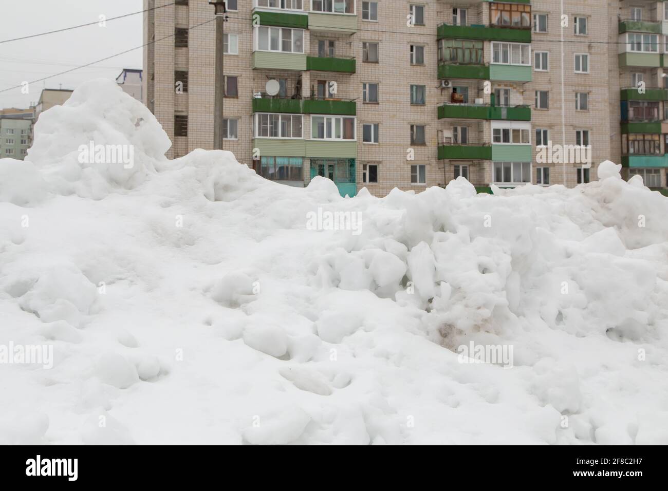 A large snowdrift in the city against the background of a multi-storey ...