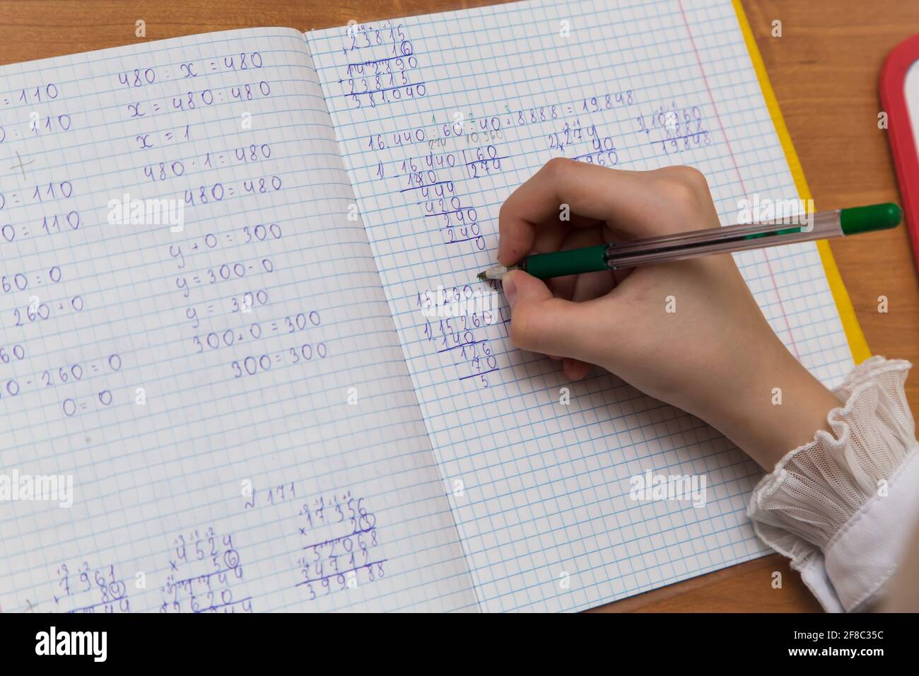 A girls hand with a fountain pen solves examples in mathematics close ...