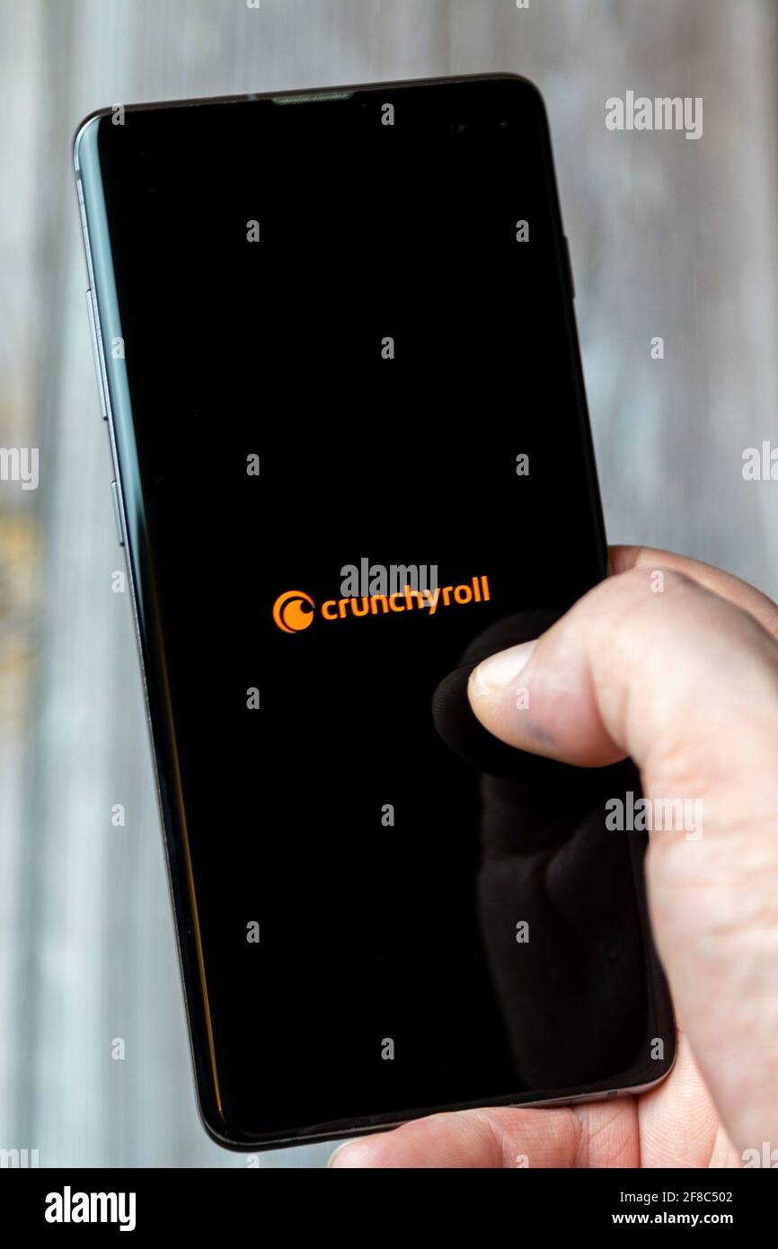 A mobile phone or cell phone being held by a hand with the Crunchyroll ...