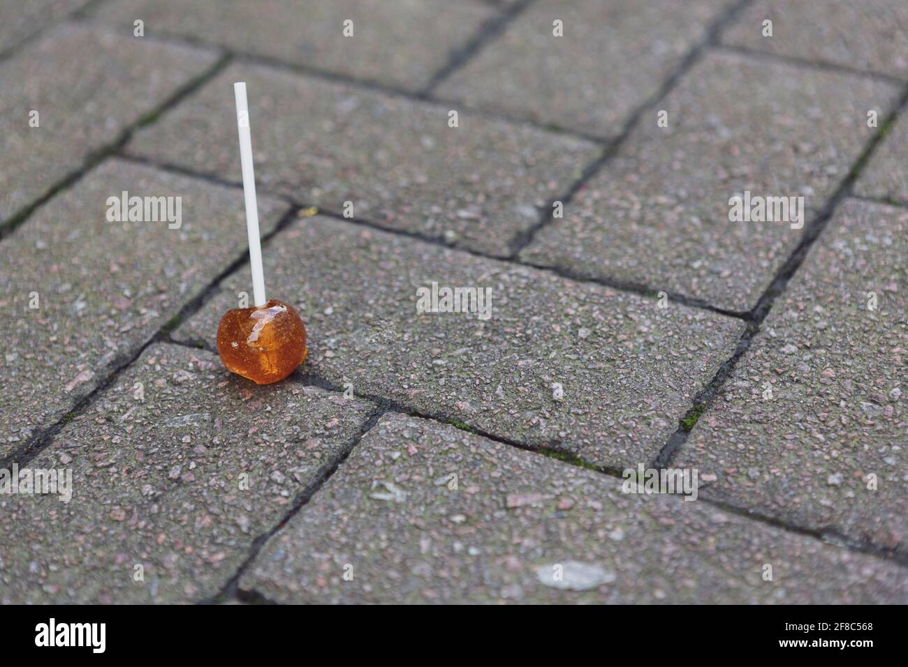 A children's sticky lollipop upside down on pavement Stock Photo - Alamy
