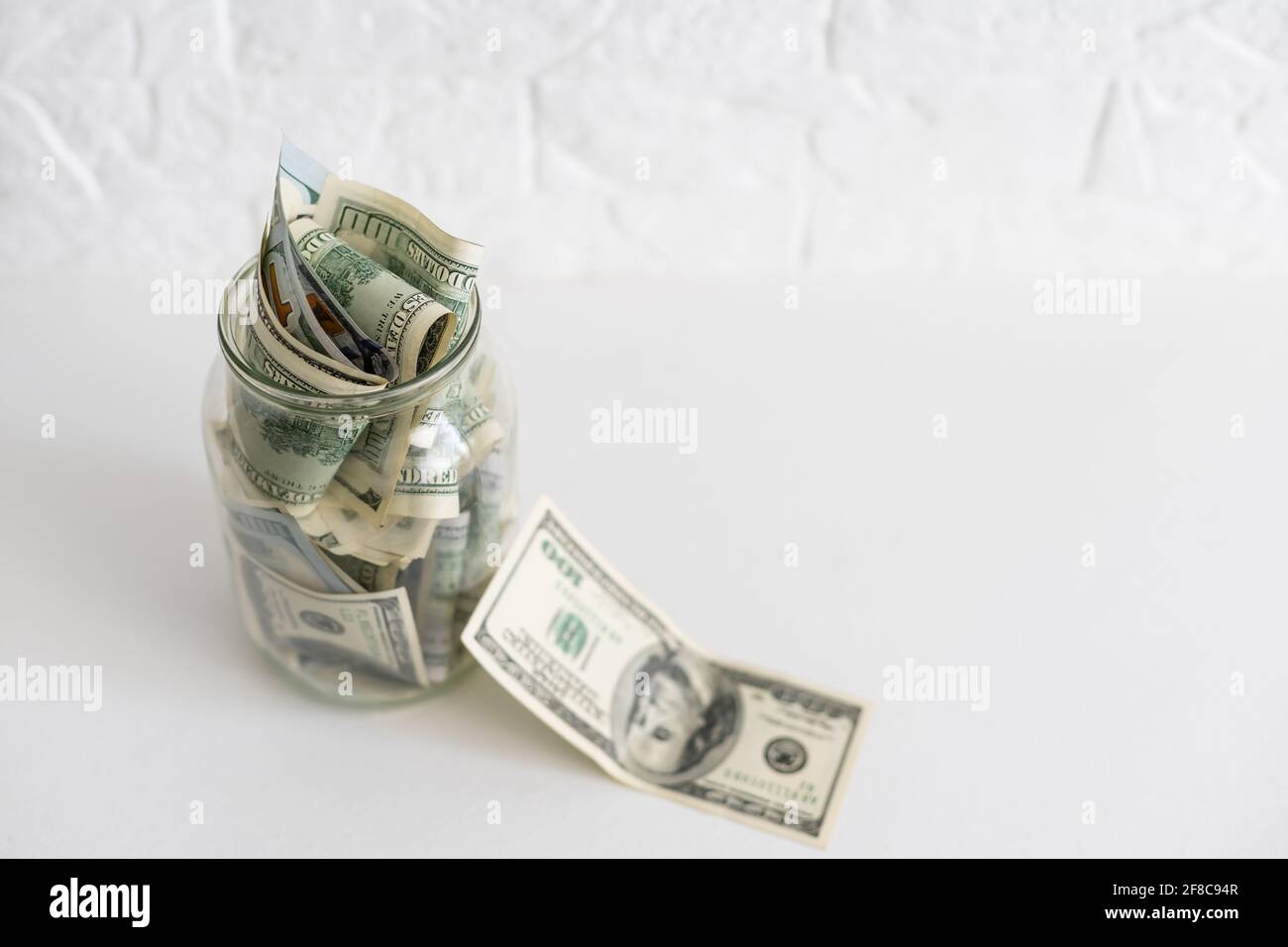 Many dollars bank notes in a glass jar isolated on white background ...