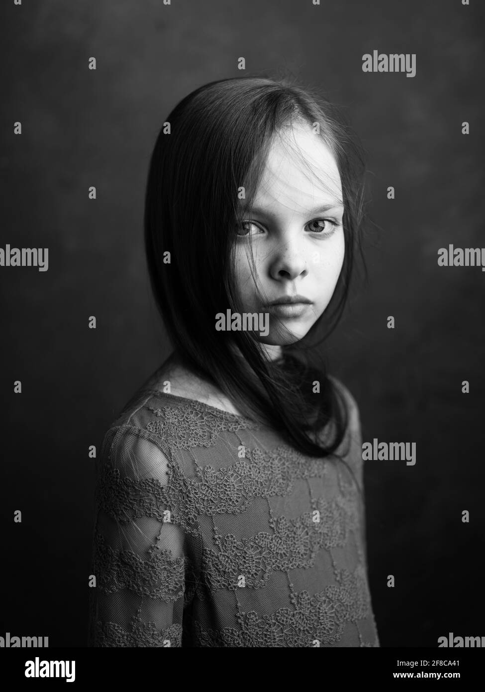 Portrait of a little girl in a dress on a dark gray background ...