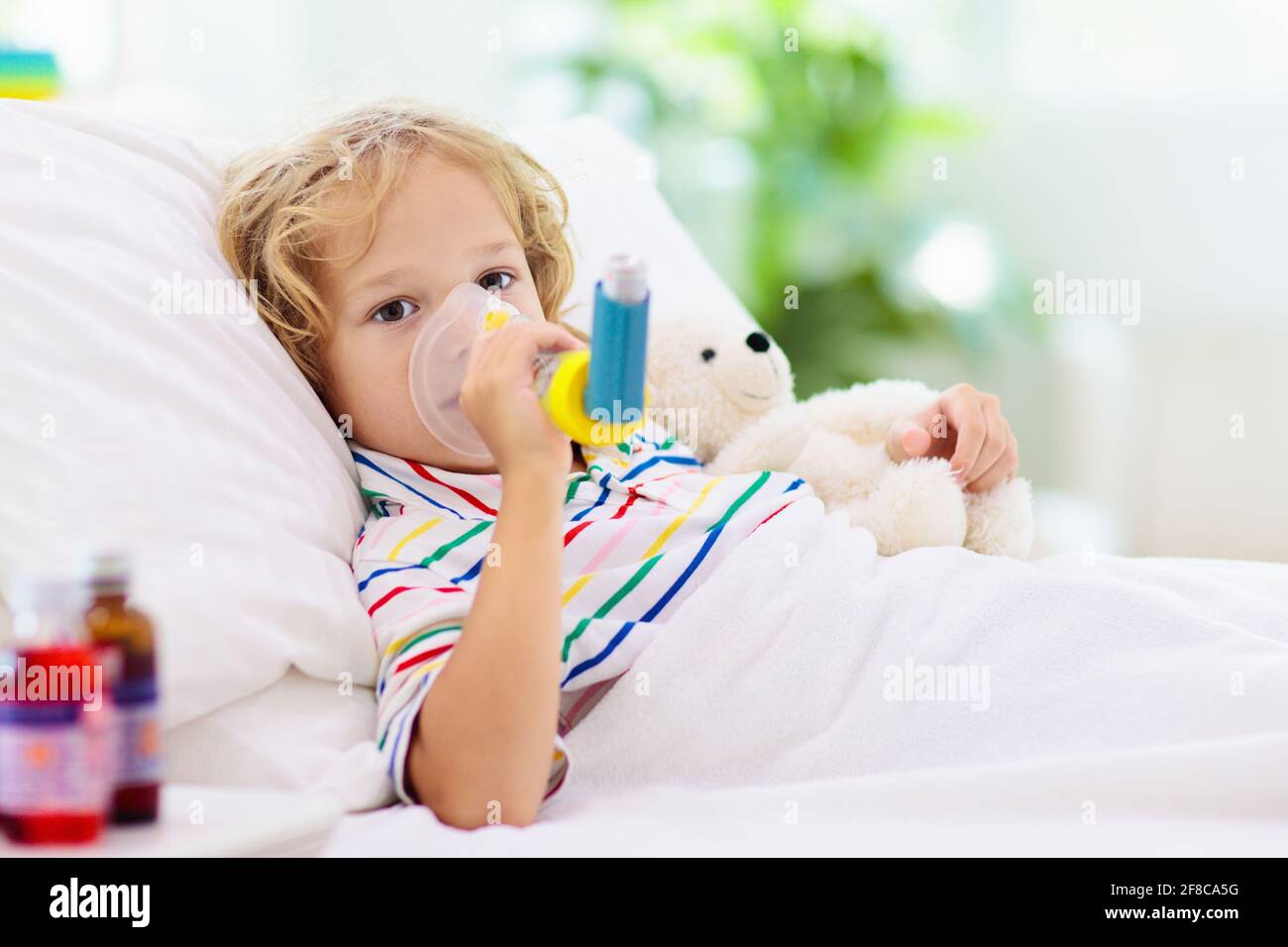 Sick little boy with asthma medicine. Ill child lying in bed. Unwell ...