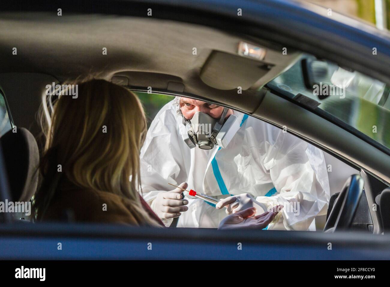 Woman sitting in car, waiting for medical worker to perform drive-thru ...