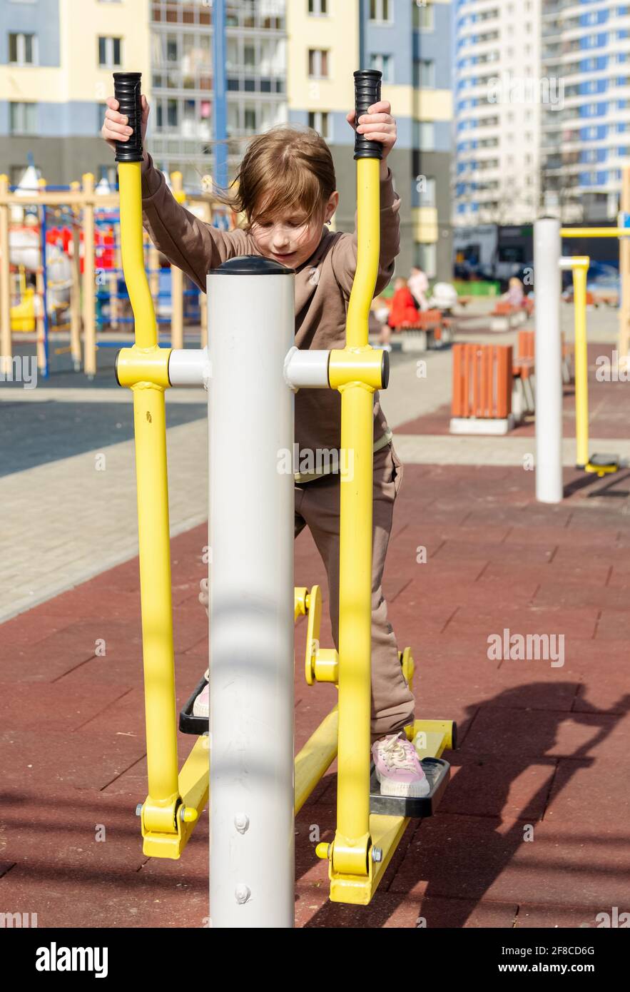 Adorable little kid girl making exercises on sports training apparatus ...