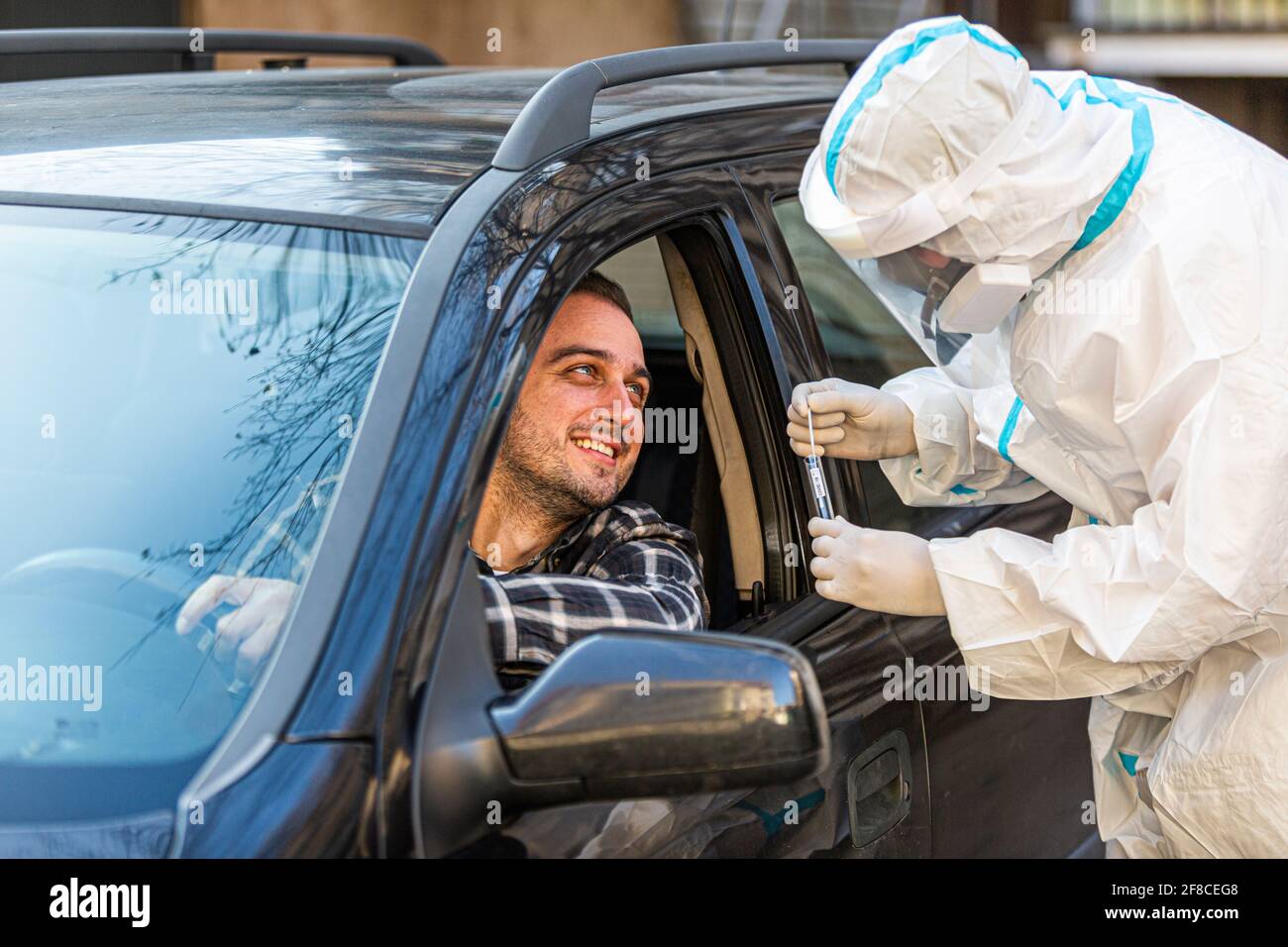 Man sitting in car, waiting for medical worker to perform drive-thru ...