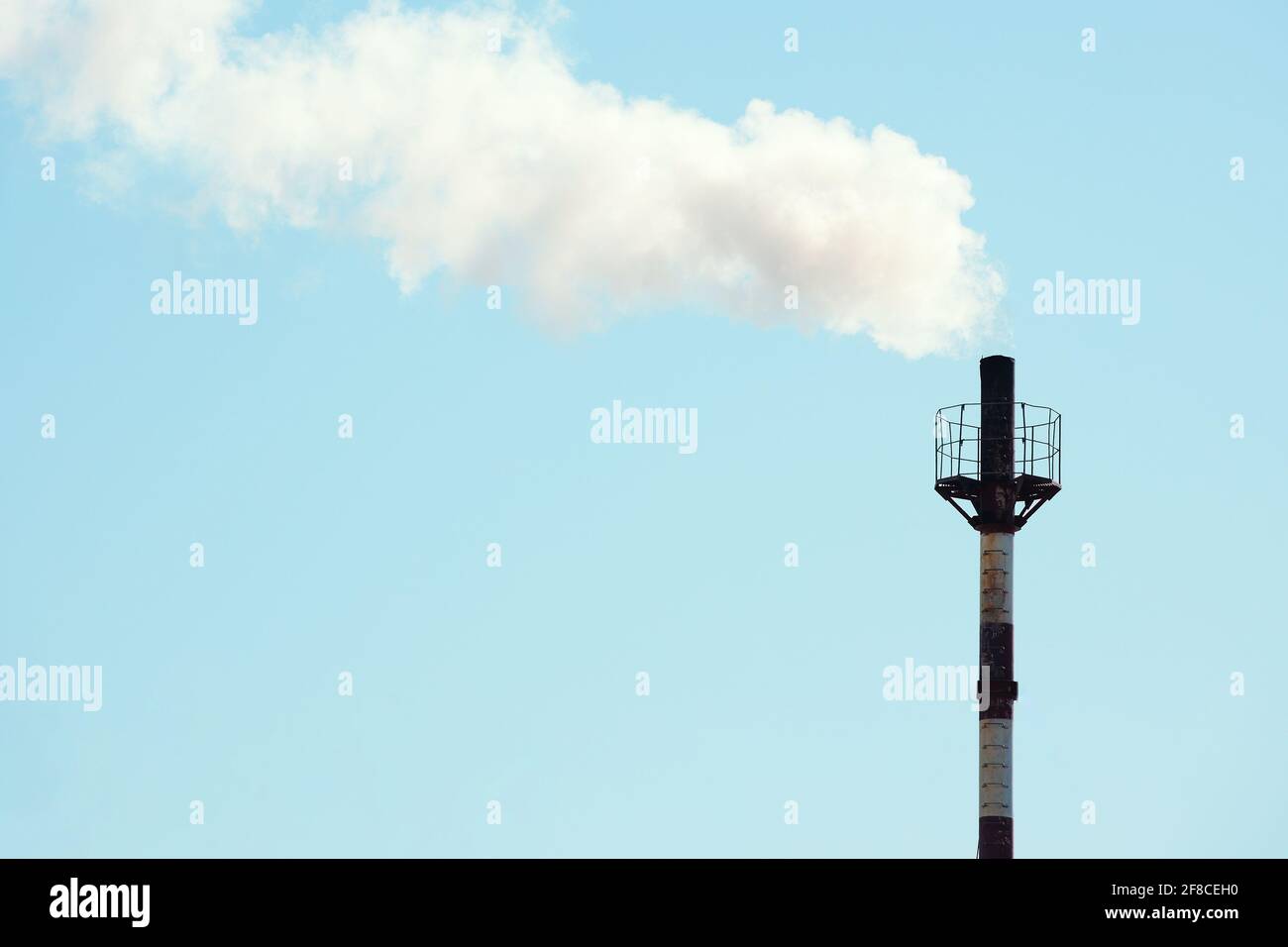 Smoke is coming from the gas boiler room pipe against the blue sky. The ...