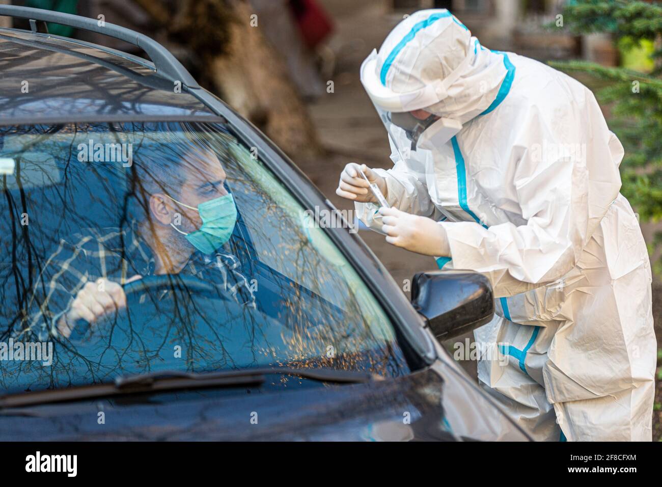 Man sitting in car, waiting for medical worker to perform drive-thru ...