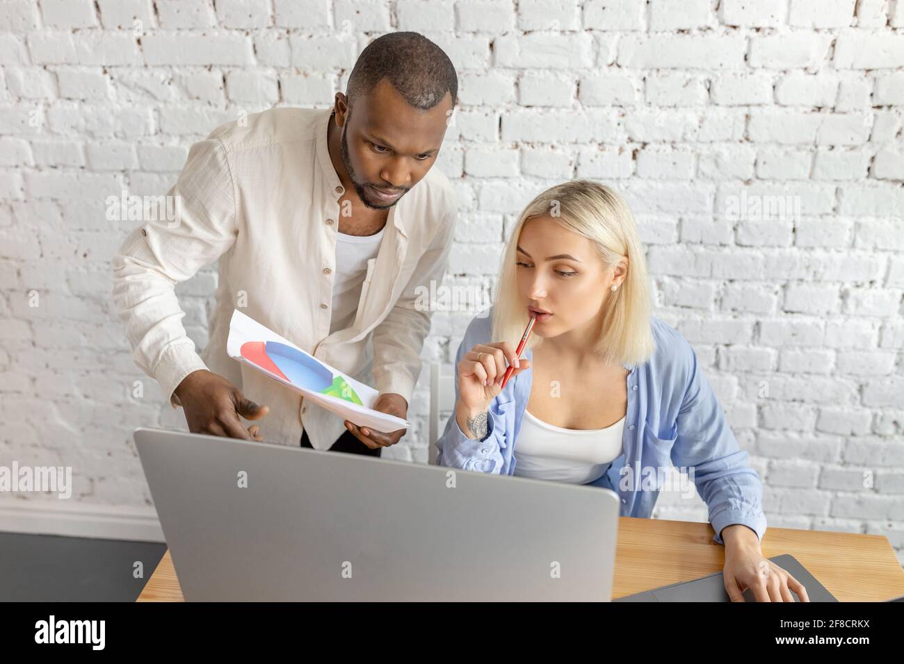 Concentrated coworkers using laptop, discussing a project, learning ...