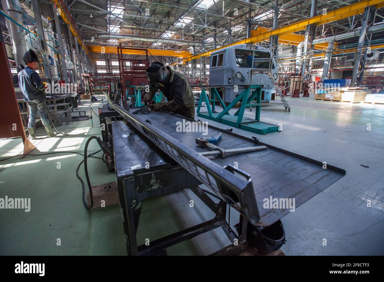 Locomotive-building plant workshop. Two Asian welder workers make metal ...