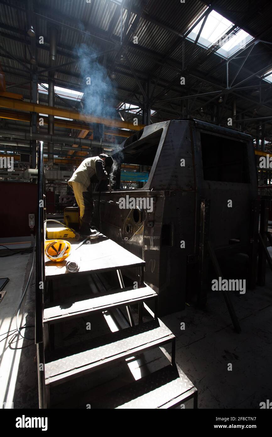 Locomotive-building plant. Welder worker in mask making metalworks with ...