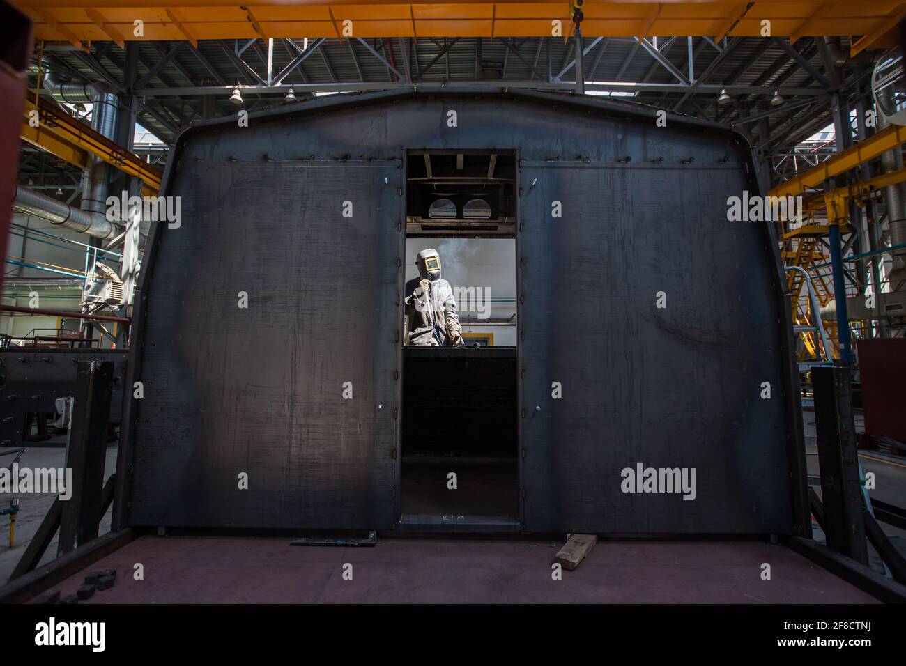 Locomotive-building plant. Welder worker in mask making metalworks with ...