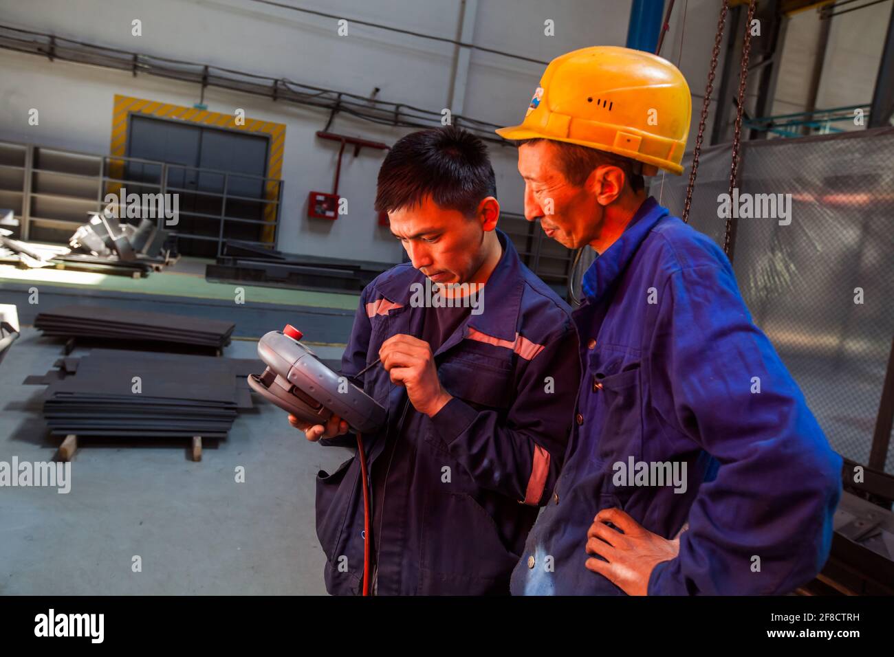 Locomotive-building plant. Two Asian workers programming CNC machine ...