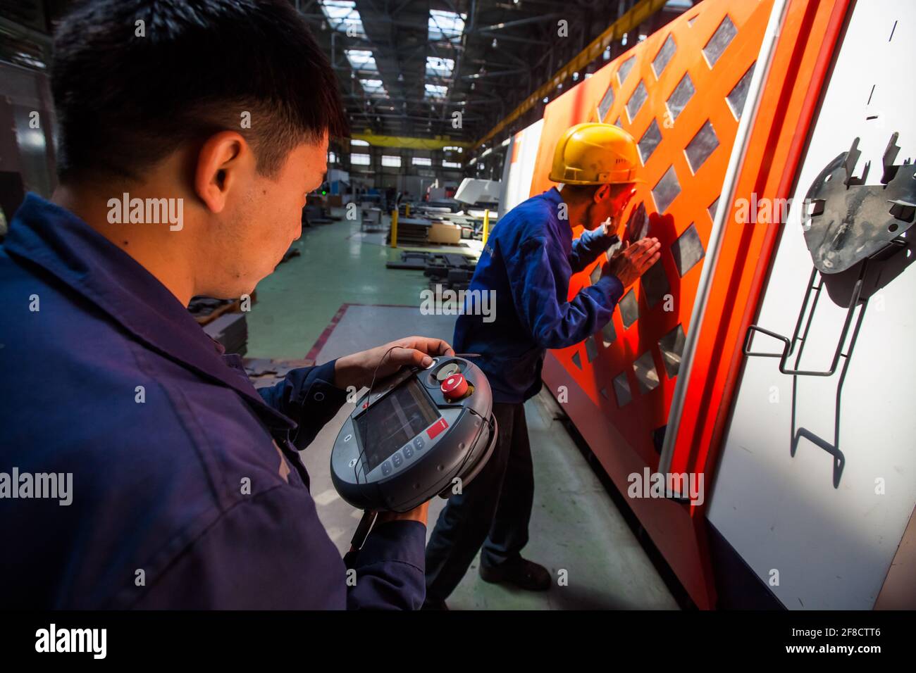Locomotive-building plant. Two Asian workers programming CNC machine ...