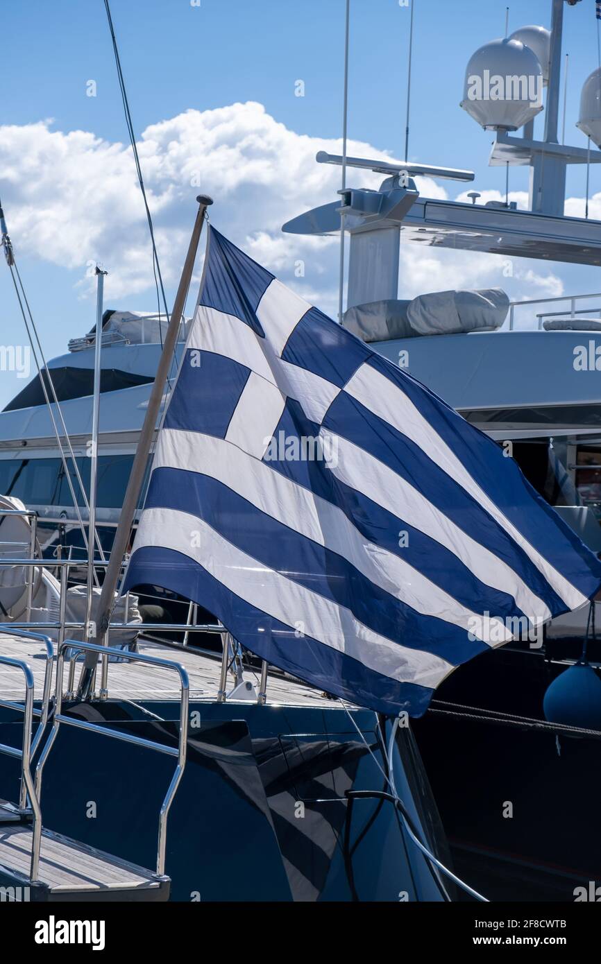 Greek flag on a luxury boat anchored in a marina in Greece. Blue white ...