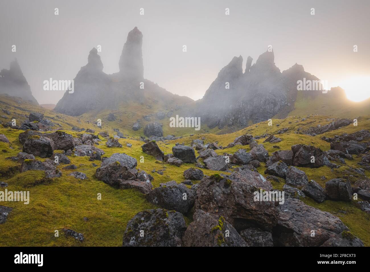 A misty, atmospheric, rocky landscape with golden sunrise light at the ...
