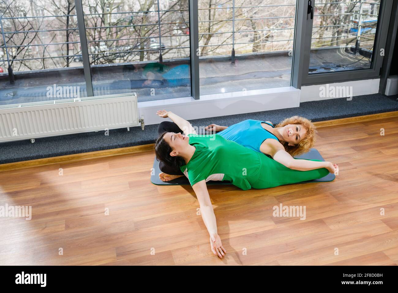 Two women make yoga stretching together indoors Stock Photo - Alamy