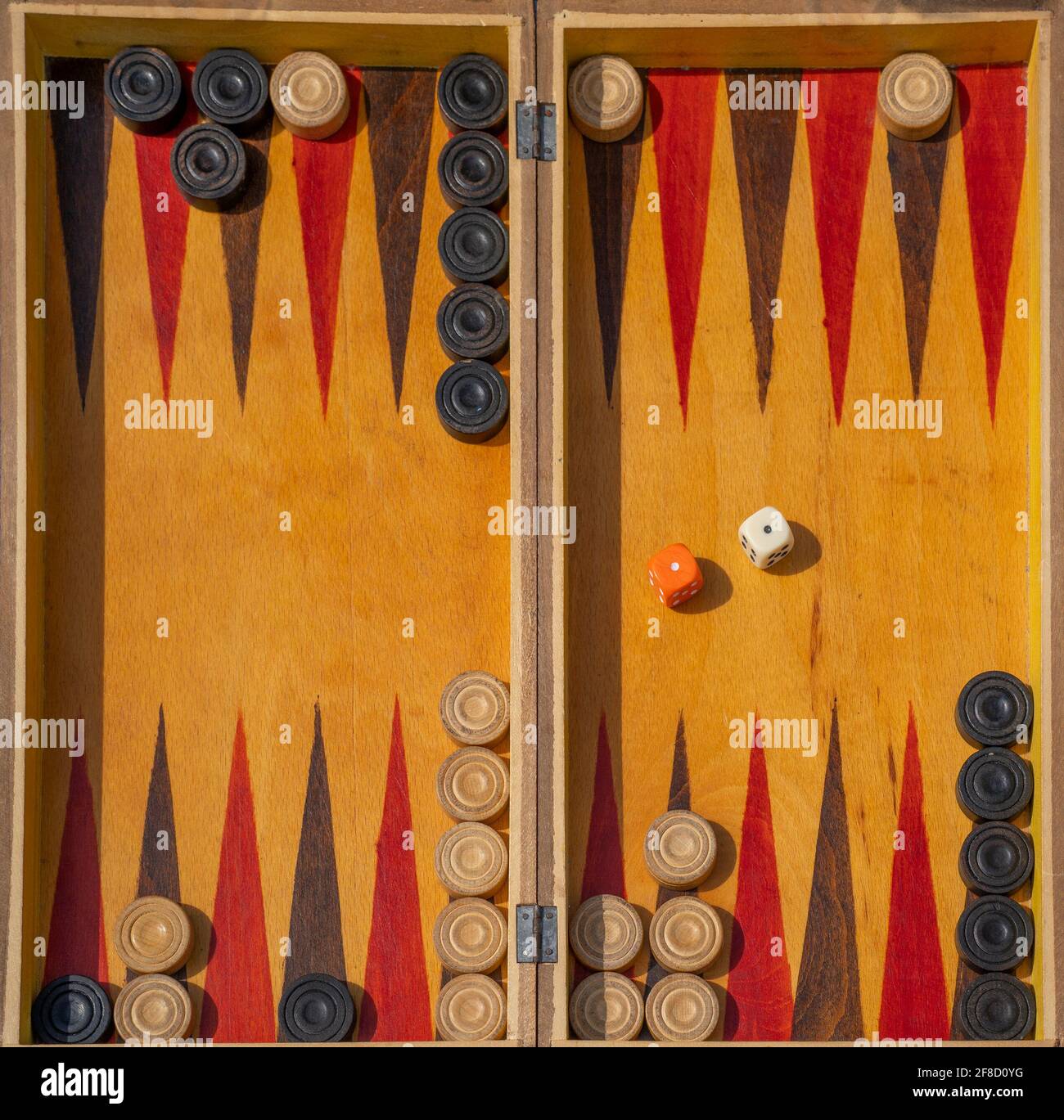 A wooden backgammon board marked brown and red, with wooden game pieces ...