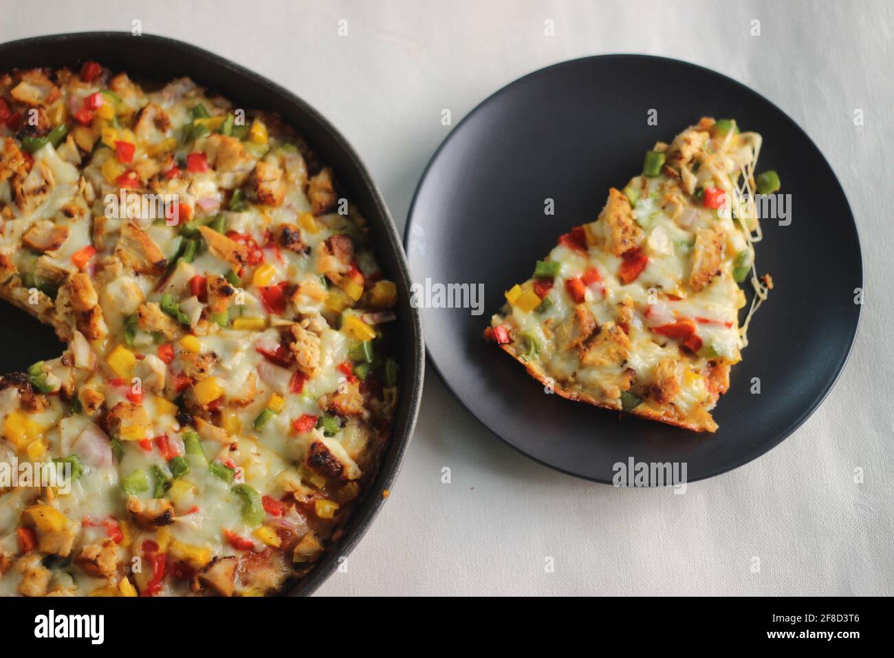 A thin crust homemade pizza loaded with cheese, chicken and vegetables ...