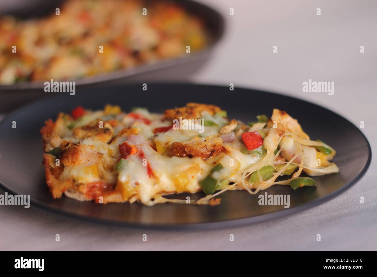 A thin crust homemade pizza loaded with cheese, chicken and vegetables ...