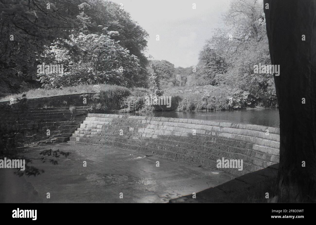 1950s, historical, on a summer's day, a view of a stepped wall or weir ...