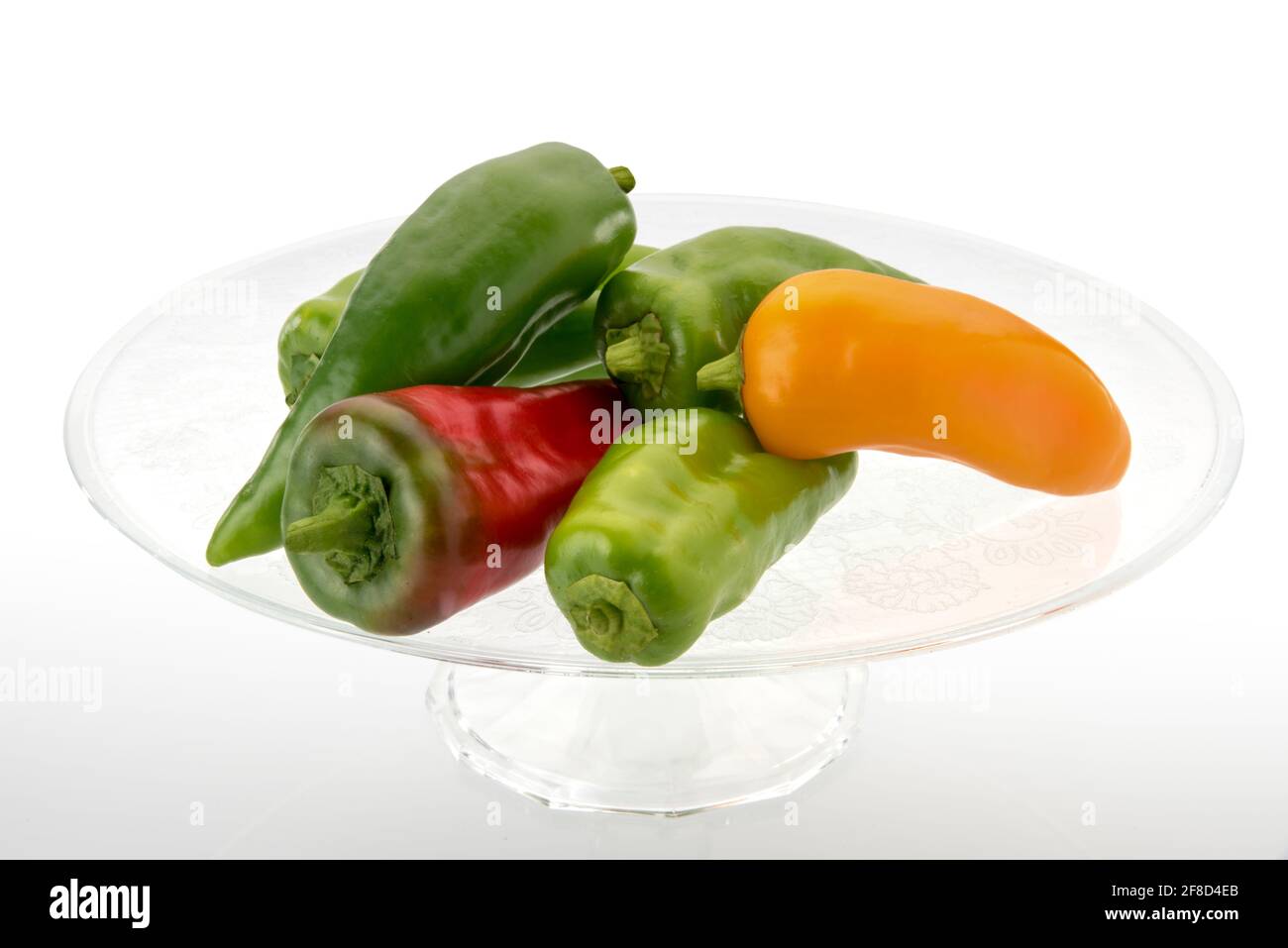 Pointy peppers on clear glass raised plate. Red, yellow and green ...