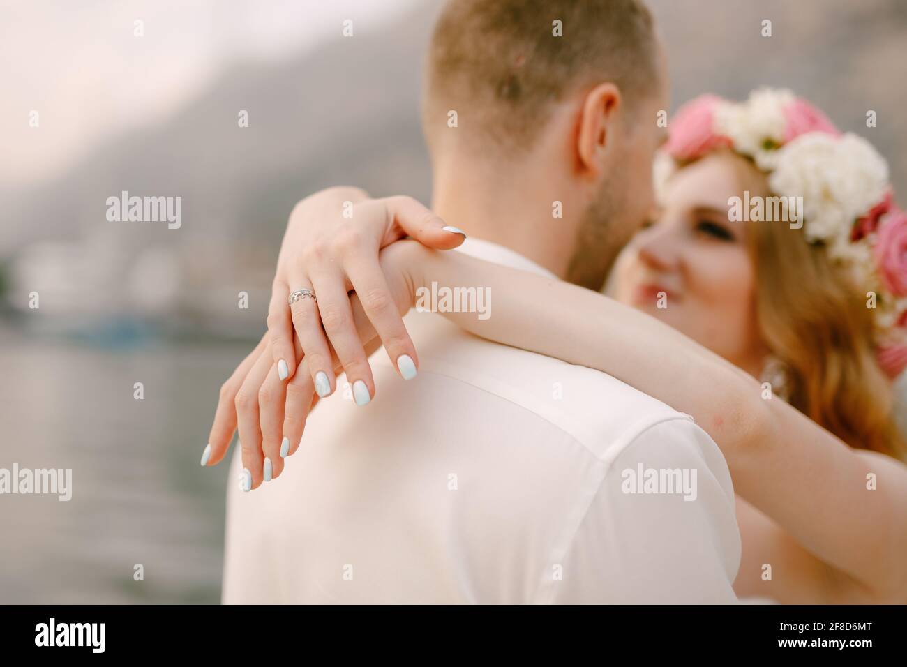 The bride and groom hug on the pier, the bride in a delicate wreath ...