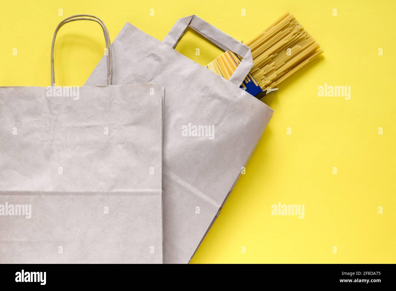 Pasta in recycled brown paper shopping bag with handle, on yellow ...