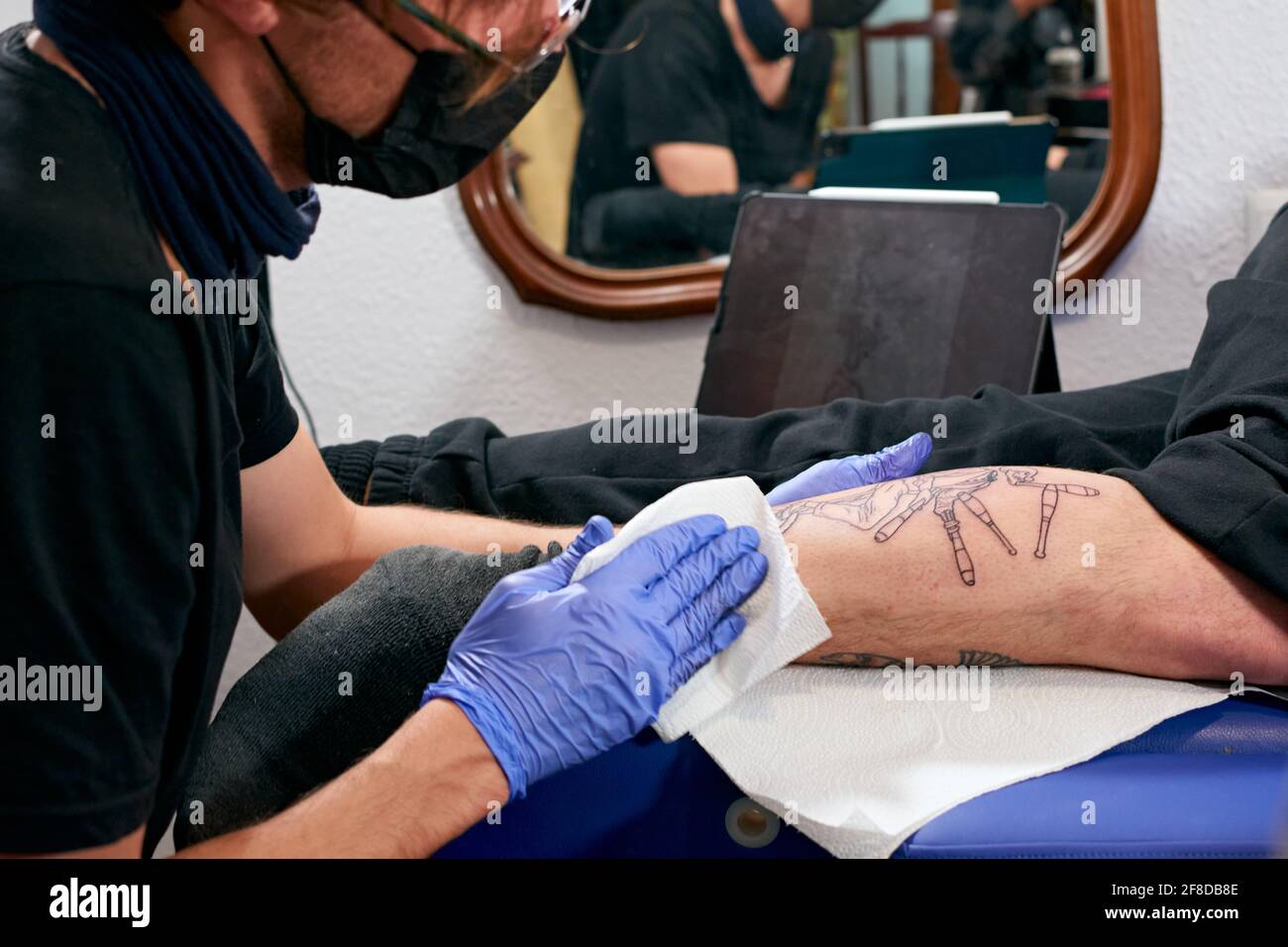 Tattoo artist in blue gloves cleaning the newly completed tattoo on a ...