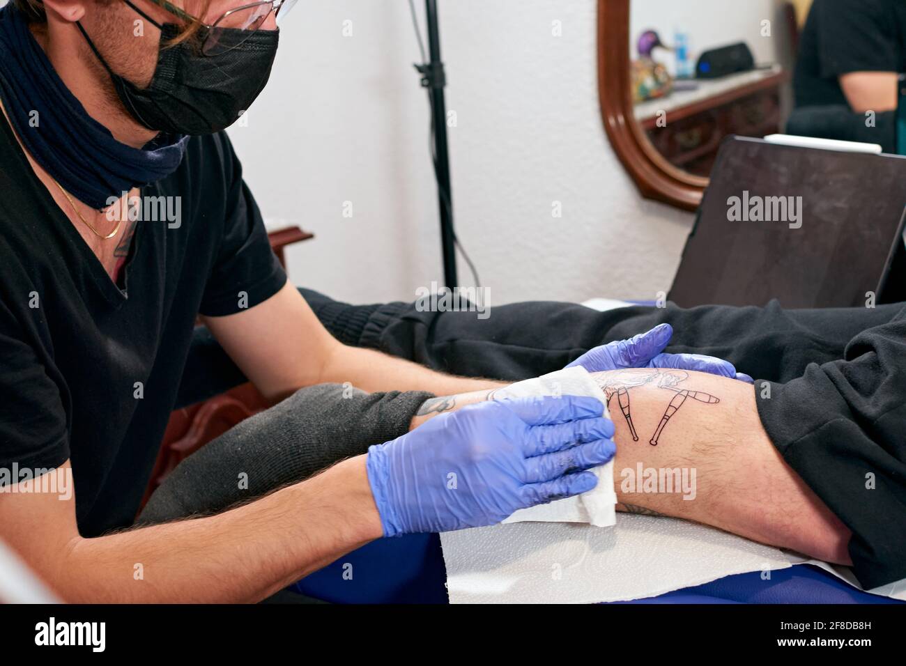 Tattoo artist in blue gloves cleaning the newly completed tattoo on a ...