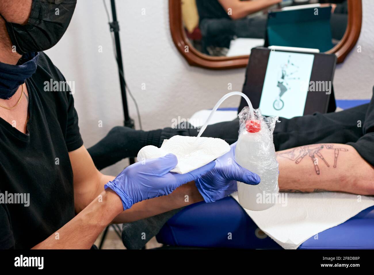 Tattoo artist in blue gloves cleaning the newly completed tattoo on a ...