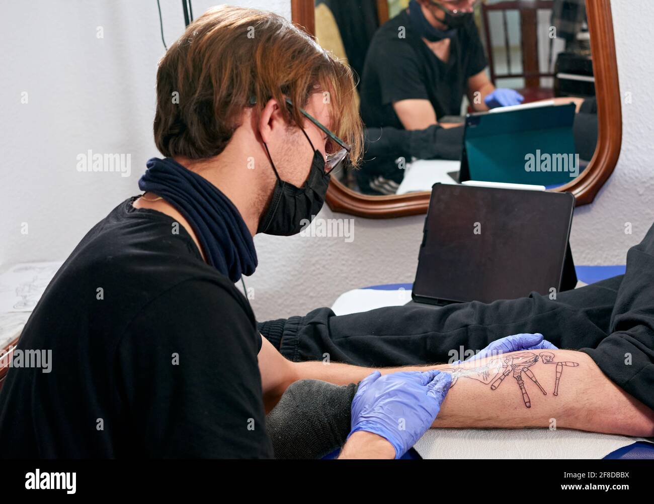 Tattoo artist in blue gloves cleaning the newly completed tattoo on a ...