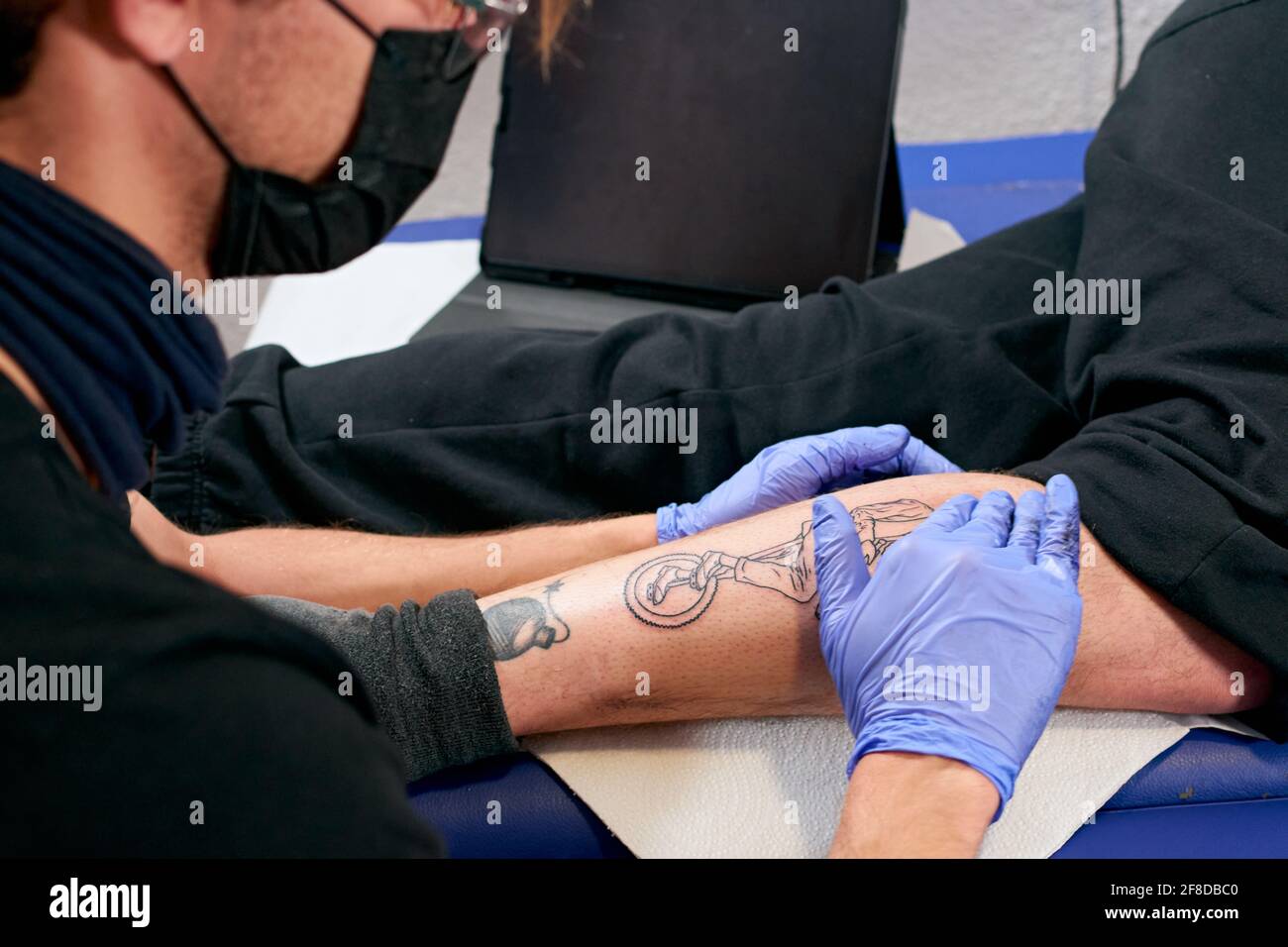 Tattoo artist in blue gloves cleaning the newly completed tattoo on a ...
