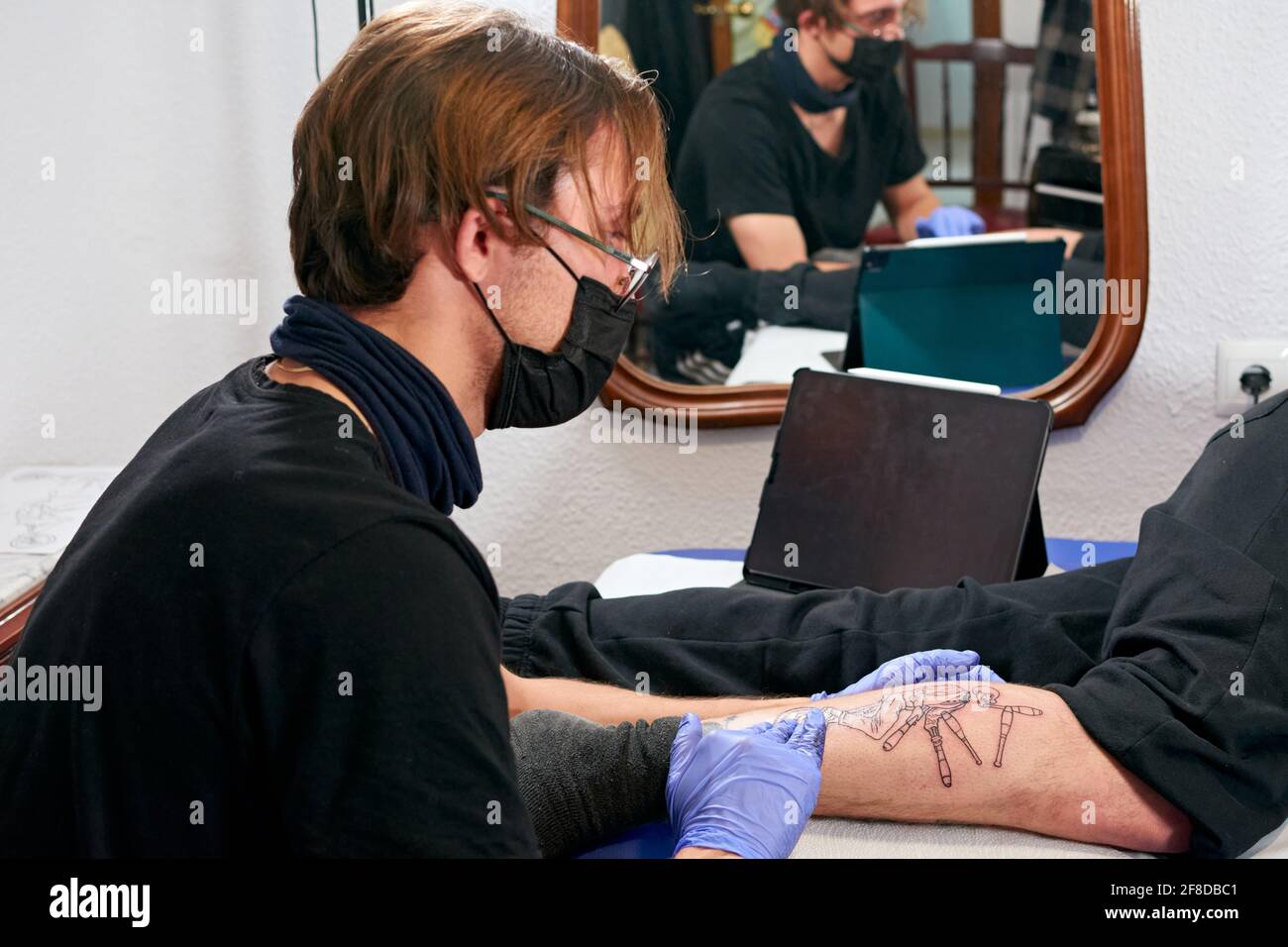 Tattoo artist in blue gloves cleaning the newly completed tattoo on a ...