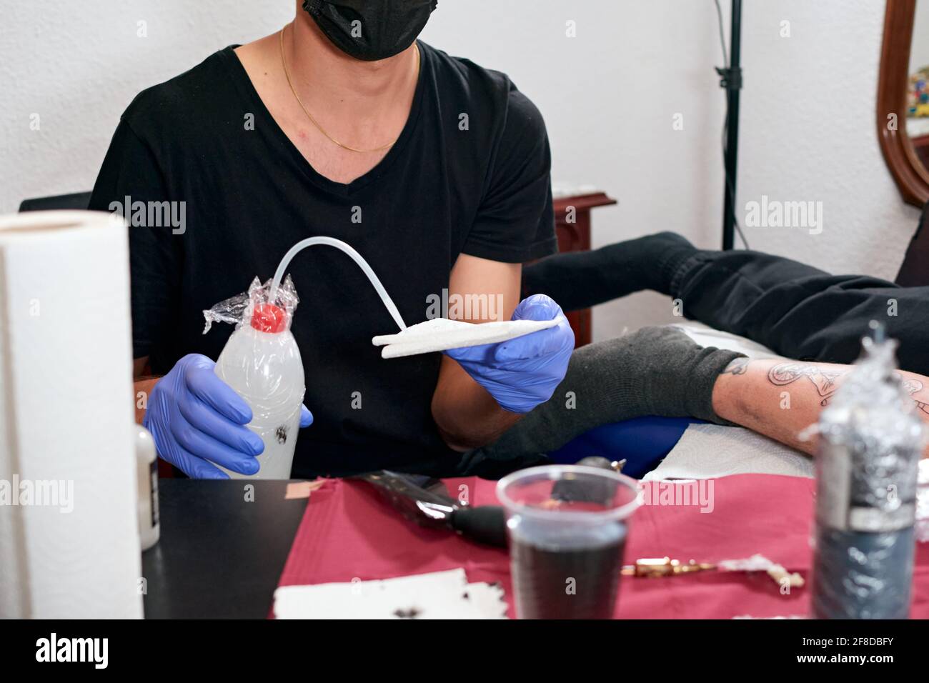 Tattoo artist in blue gloves cleaning the newly completed tattoo on a ...